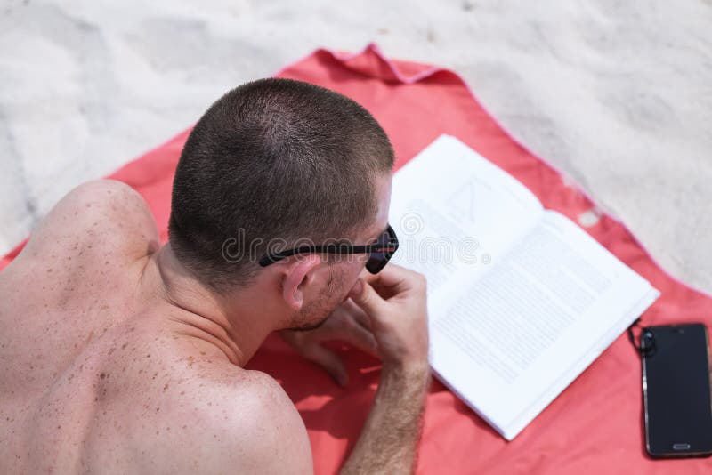 Man Reading a Book while Relaxing on Picnic Blanket at Beach Stock ...