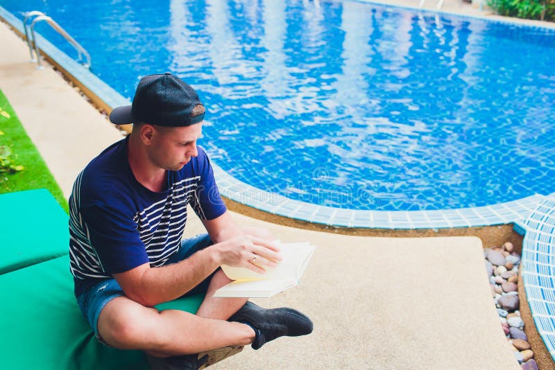 A Man Reading Book beside Swimming Pool in the Garden. Stock Image ...