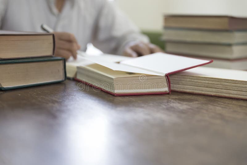 Man Reading Book with Textbook Stack on Wooden Desk Stock Photo - Image ...
