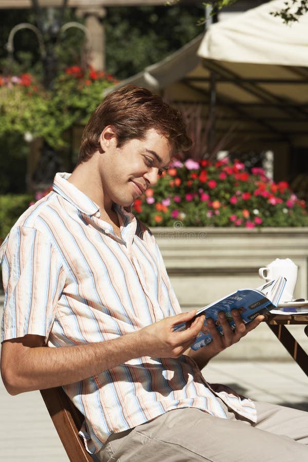Man Reading Guidebook at Outdoor Cafe Stock Photo - Image of brunette ...