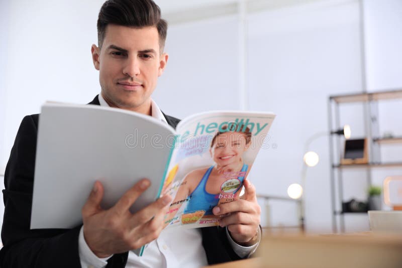 Man Reading Magazine at Table in Office Stock Photo - Image of indoors ...