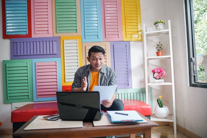 Man Reading Paperwork while Using Laptop in Co-working Space Stock ...