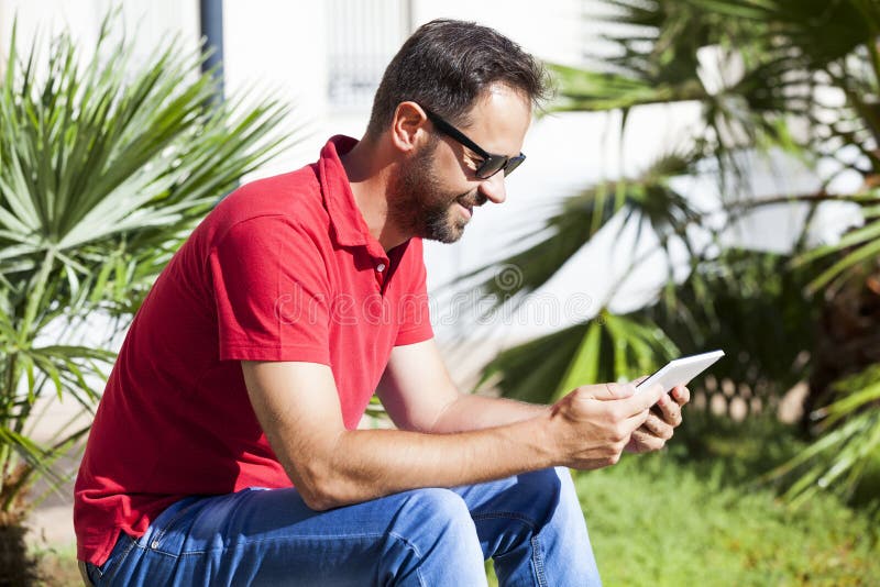 Man Reading Tablet Sitting in a Bench. Stock Photo - Image of light ...
