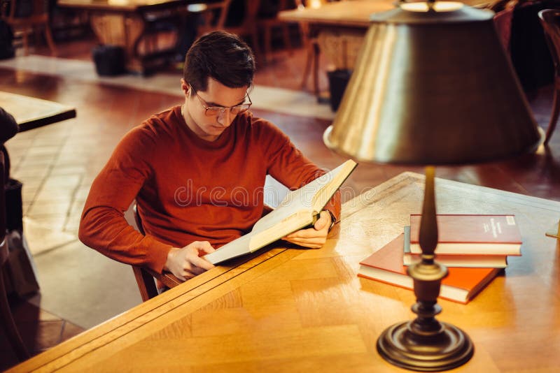Man Reads a Book Doing Study Research Sitting on Public Library Table ...