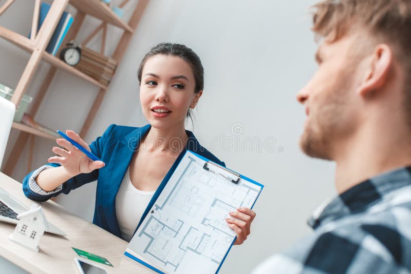 Man at Real Estate Agency Sitting Agent Explaining Layout To Client ...
