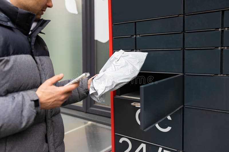 Man Receiving Parcel from Automatic Post Box Using Smartphone Outdoors ...