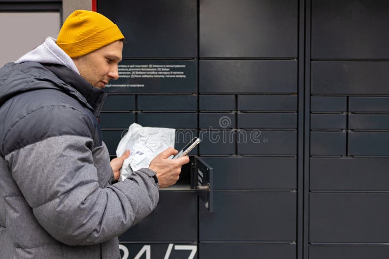 Man Receiving Parcel from Automatic Post Box Using Smartphone Outdoors ...