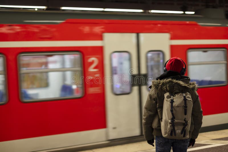 A Man with a Red Cap and Headphones Waiting for the S-Bahn Train at the ...