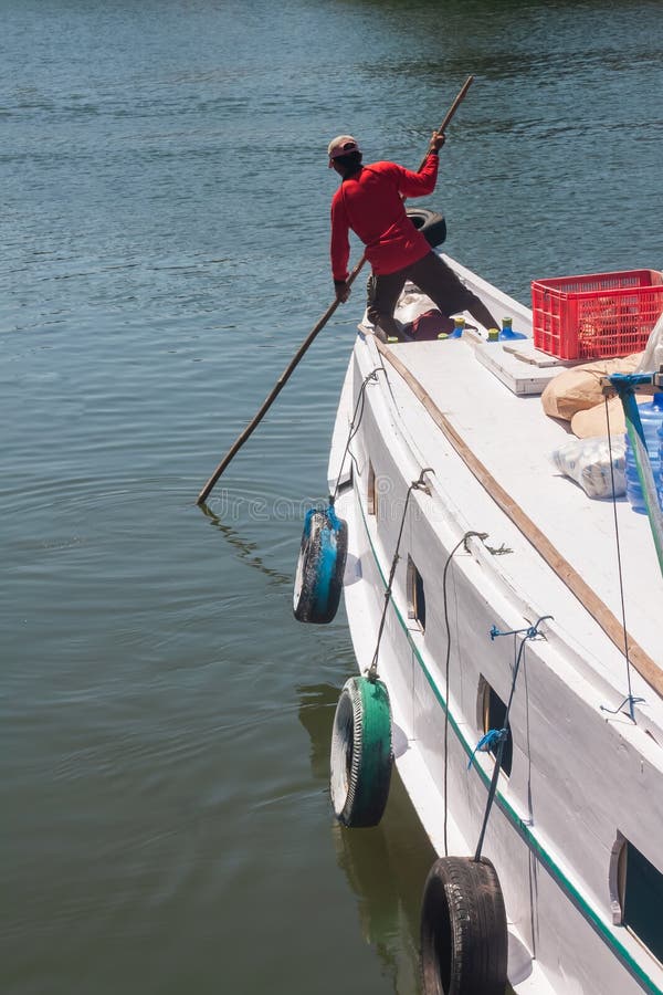 A Man in Red Using a Long Stick Prepares His Boat To Cross a Large ...