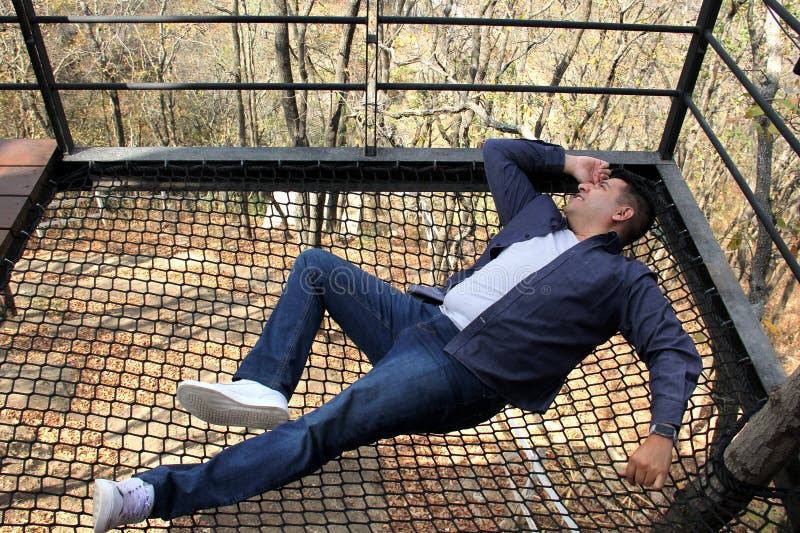 Man Relaxes in a Hanging Net of a Glamping Cabin in the Middle of the ...