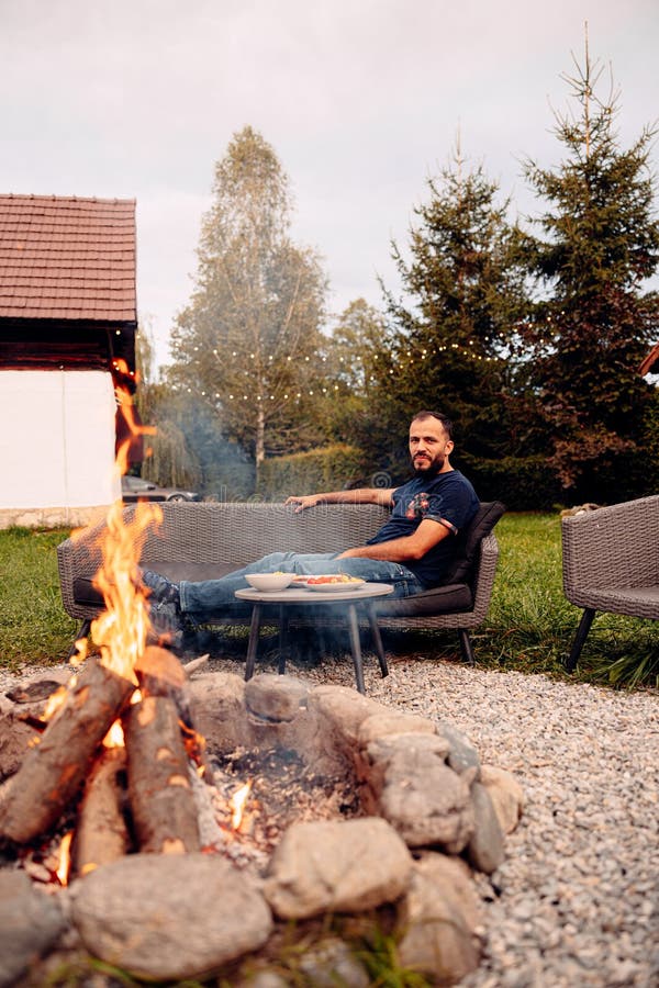 Man Relaxing by a Backyard Fire Pit Stock Photo - Image of bonfire ...