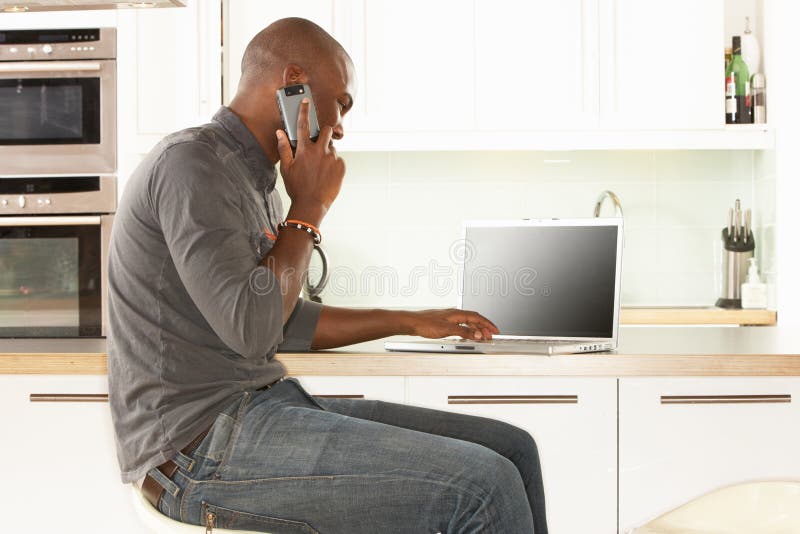 Man Using Laptop and Talking on Phone in Kitchen at Home Stock Image ...
