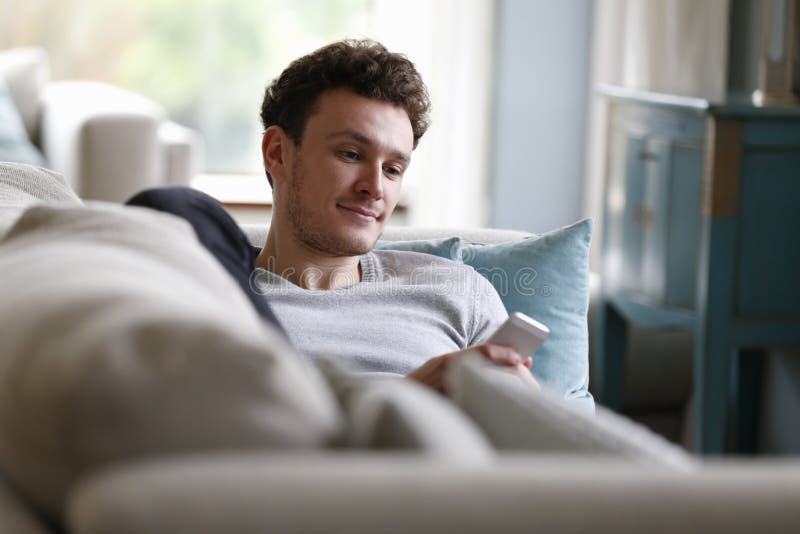 Man Relaxing on Sofa Checking Mobile Phone Stock Photo - Image of ...
