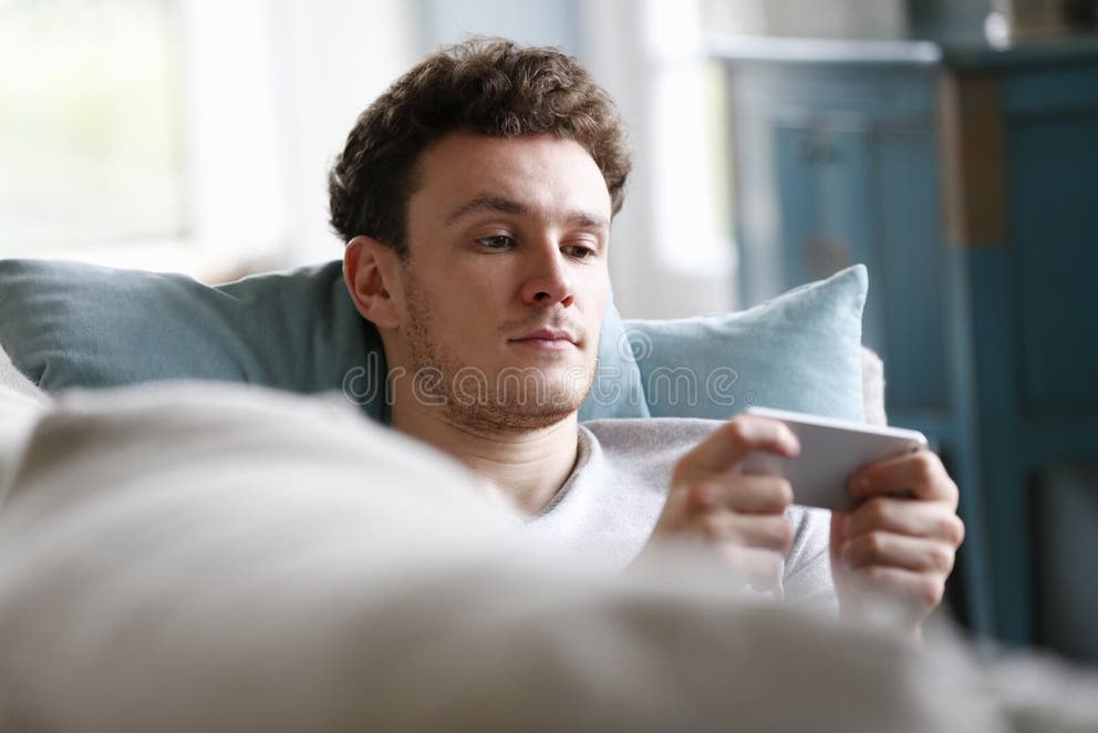 Man Relaxing on Sofa Checking Mobile Phone Stock Image - Image of ...