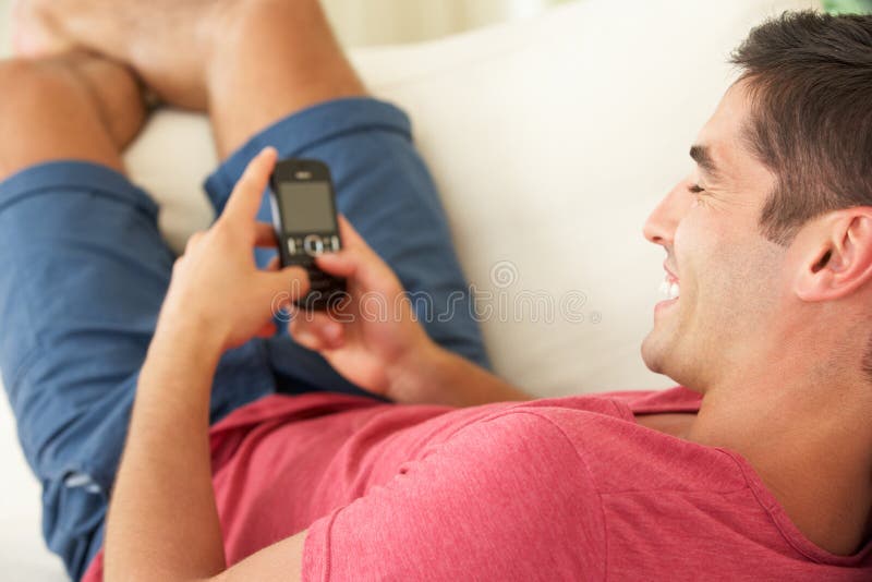 Man Relaxing on Sofa Sending Text Message Stock Image - Image of ...