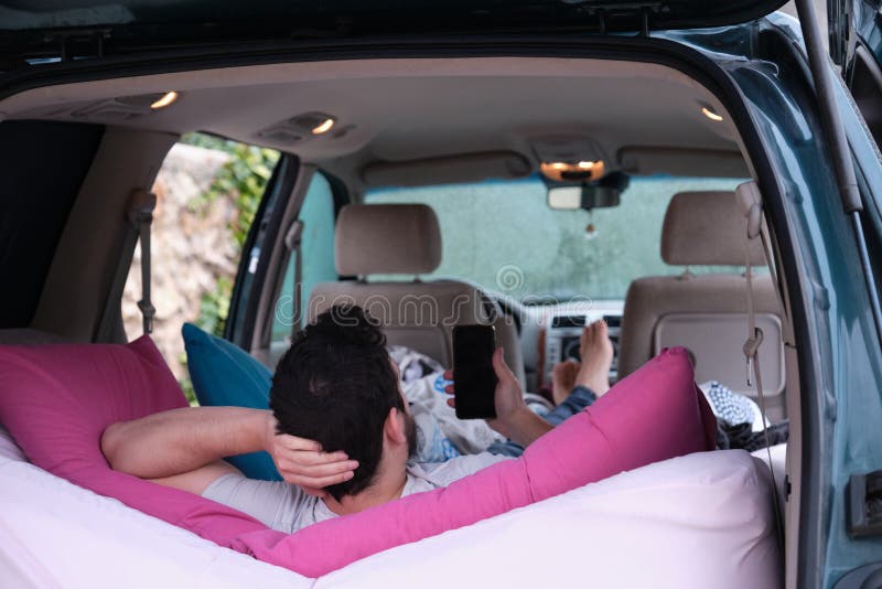 Man Relaxing and Using His Smartphone in a Bed Inside His Car Stock ...