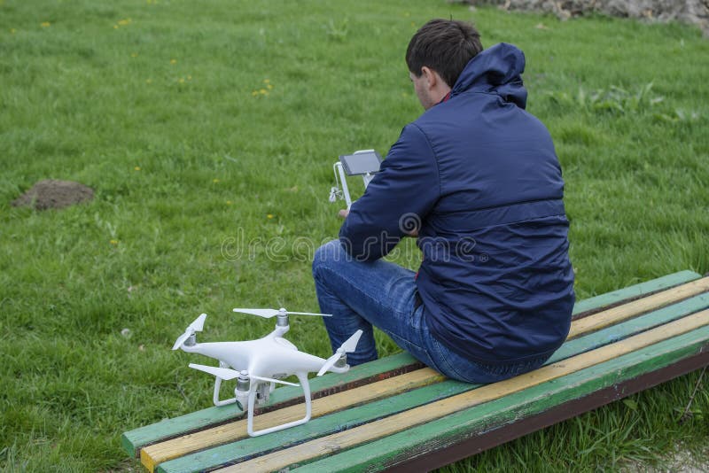 A Man with a Remote Control Quadroopter in His Hands is Sitting on a ...