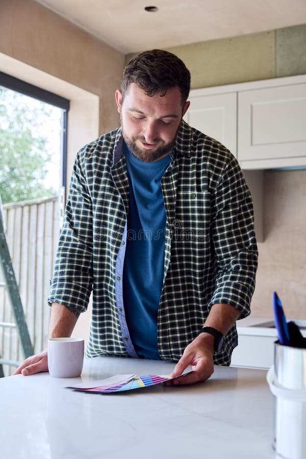 Man Renovating Kitchen at Home Looking at Paint Swatches on Coffee ...