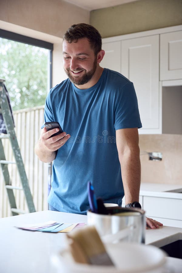 Man Renovating Kitchen at Home with Paint Swatches Using Mobile Phone ...