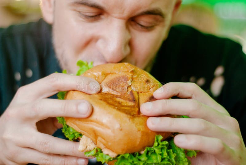 Man in a Restaurant Eating a Hamburger, he is Hungry and Having a Good ...