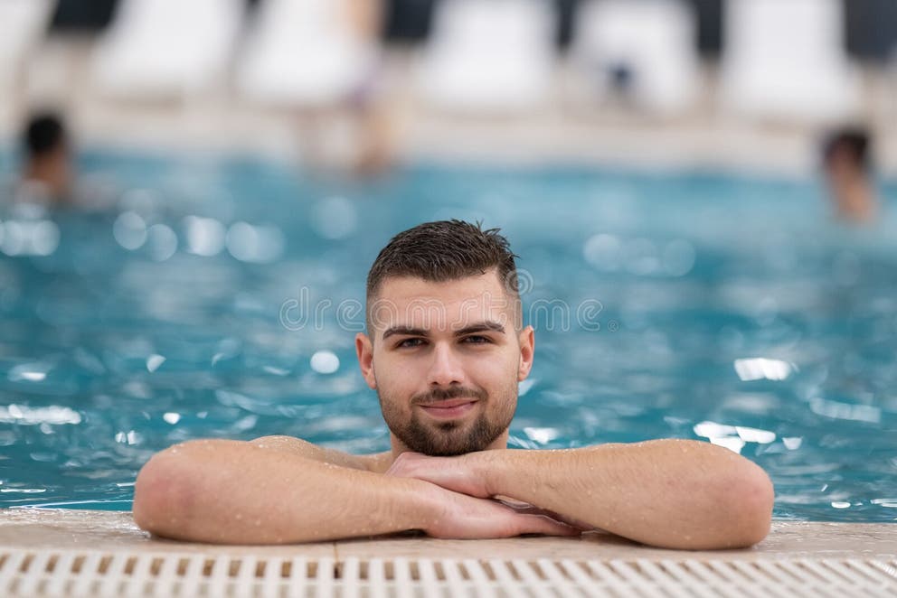 Man Resting on the Edge of a Large Indoor Pool with a Calm Expression ...