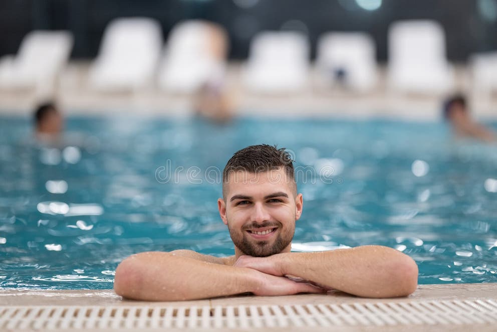 Man Resting on the Edge of a Large Indoor Pool with a Calm Expression ...