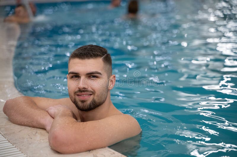 Man Resting on the Edge of a Large Indoor Pool with a Calm Expression ...