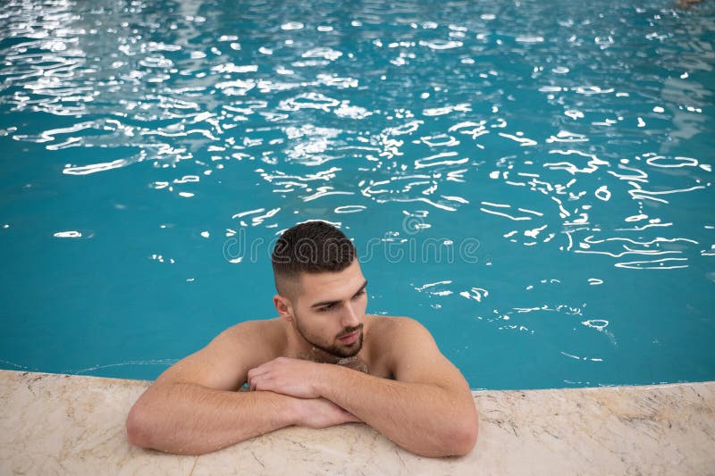 Man Resting on the Edge of a Large Indoor Pool with a Calm Expression ...