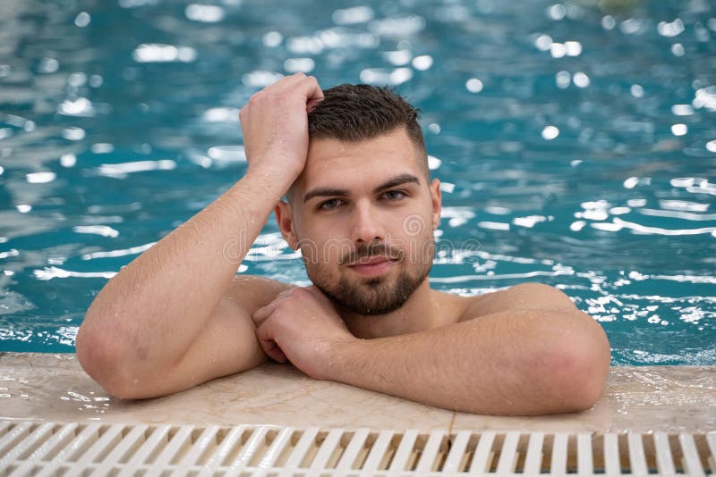 Man Resting on the Edge of a Large Indoor Pool with a Calm Expression ...