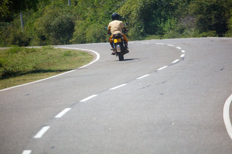 A Man is Riding a Motorcycle Down a Curvy Road Stock Photo - Image of ...