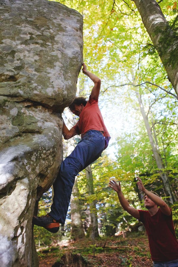 A Man Rock Climber Climbing a Rock and His Partner Insuring. Stock ...