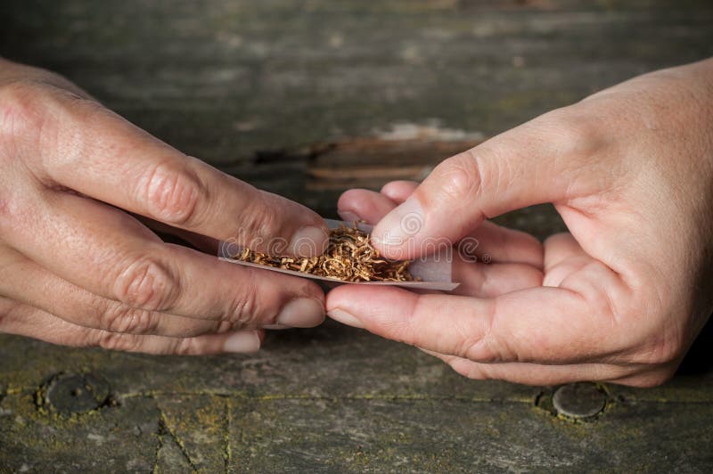 Man Rolling Cigarette on Wooden Table Stock Photo - Image of isolated ...