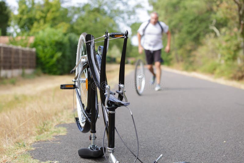 Man Rolling Wheel Towards Broken Down Bicycle Stock Image - Image of ...