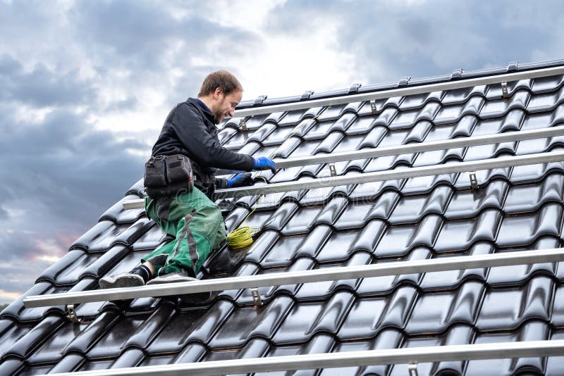 Man on the Rooftop of a House Setting Up the Mounting Structure for ...