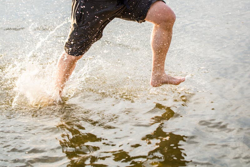 A Man Running Along a Beach and Splashing Water Stock Image - Image of ...