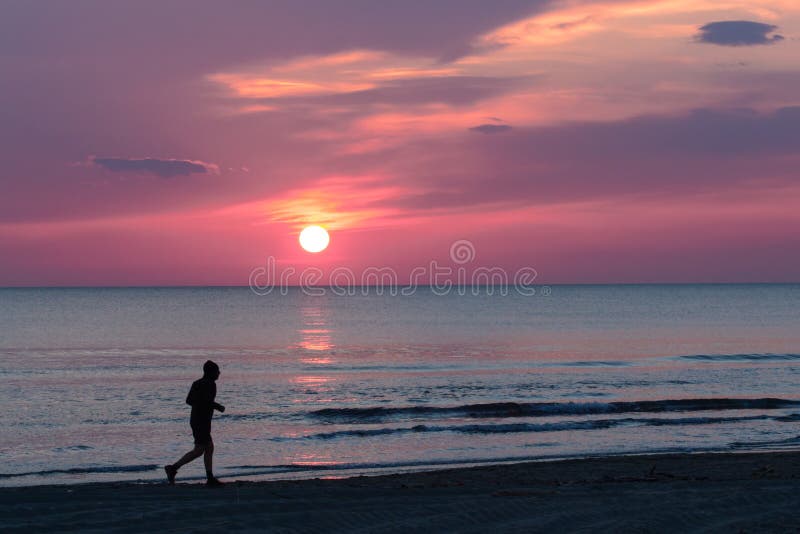 Man Running on the Beach while the Sun is Setting Stock Photo - Image ...
