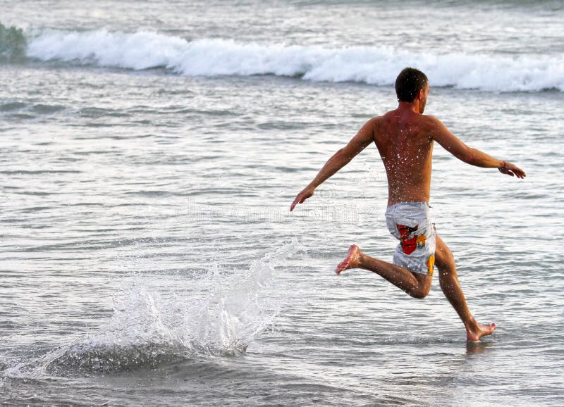 Man running into the sea editorial photography. Image of bali - 83070722