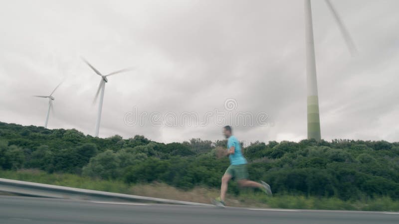 Man Runs Fast Along the Road Against Operating Wind Generators Stock ...