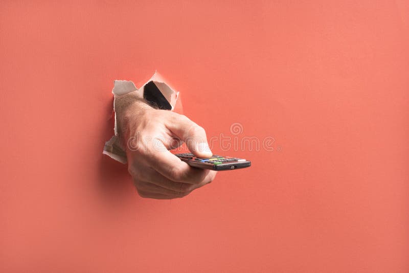 A Man`s Hand Breaks through Paper with a TV Remote Control. Control ...