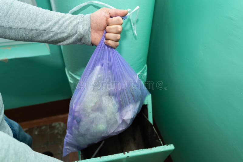 A Man`s Hand with a Garbage Bag Throws Garbage into the Garbage Chute ...