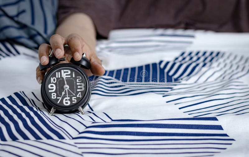 Man S Hand Holding an Alarm Clock in Bed. Time To Wake Up Stock Image ...