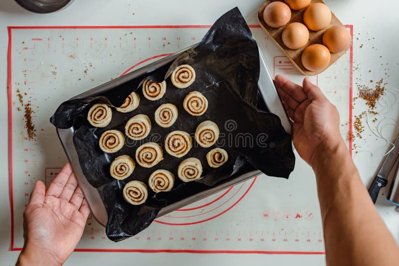 Man S Hand Holding a Tray of Cinnamon Rolls Ready To Be Put in the Oven ...
