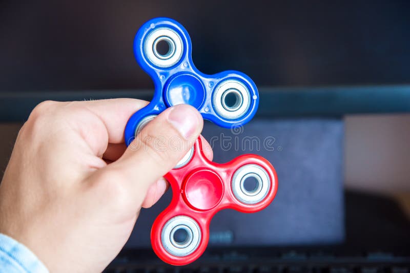 Man`s Hand Holds Two Multi-colored Spinners on the Background of a ...