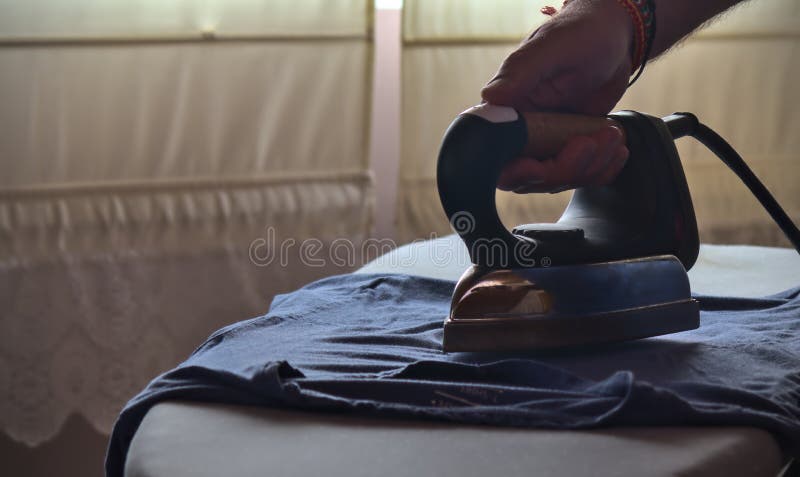 Man`s Hand with an Iron, Ironing a T-shirt, Home Sharing Concept Stock ...