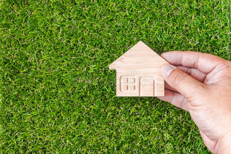 Man`s Hand Put Home Shaped on Green Grass. Green Home Concept Stock ...