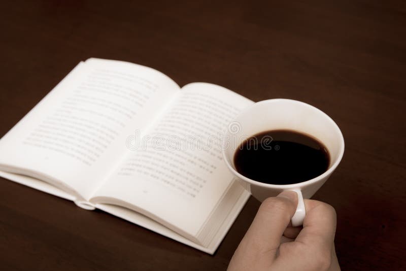 The Man`s Hand Reading with a Cup of Coffee in One Hand. Stock Photo ...