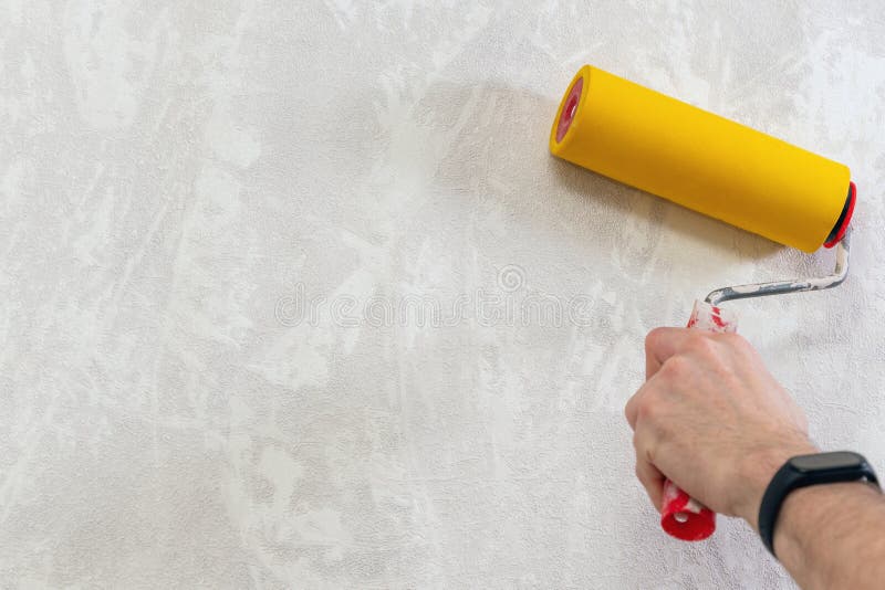 A Man S Hand with a Roller for Smoothing Wallpaper. Wallpapering the ...