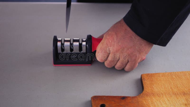 A Man S Hand Sharpens a Kitchen Knife in a Special Knife Sharpener ...