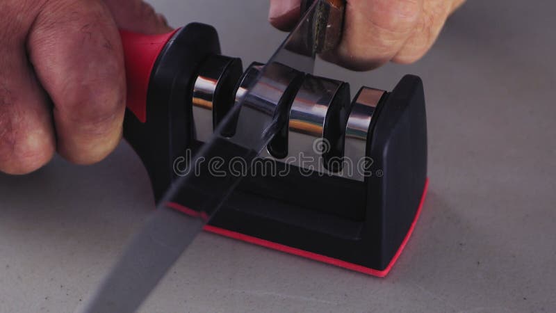 A Man S Hand Sharpens a Kitchen Knife in a Special Sharpener on the ...