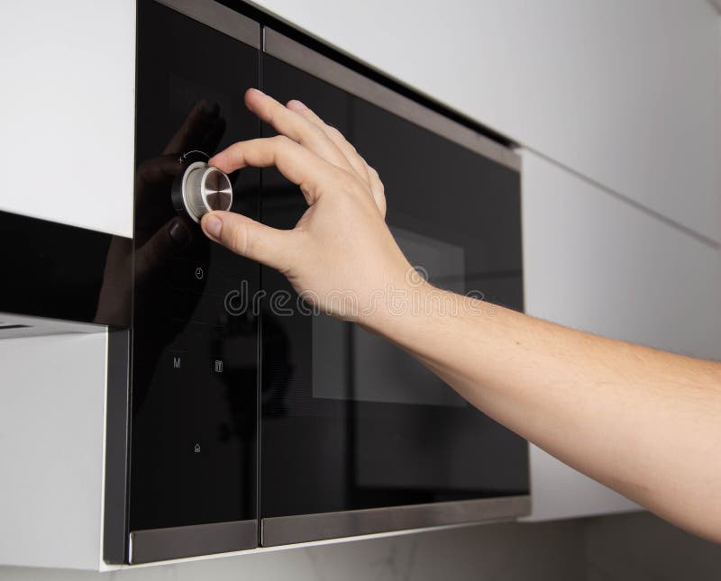 A Man& X27;s Hand Twists a Regulator Button on a Modern Microwave Oven ...